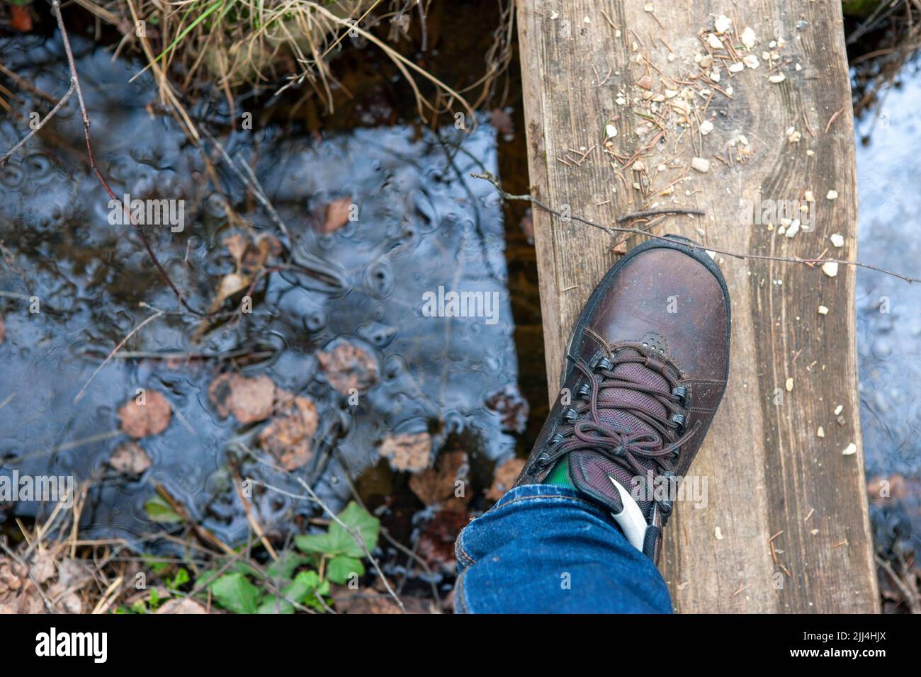 overhead shot of a male foot wearing boot crossing stream or river ...