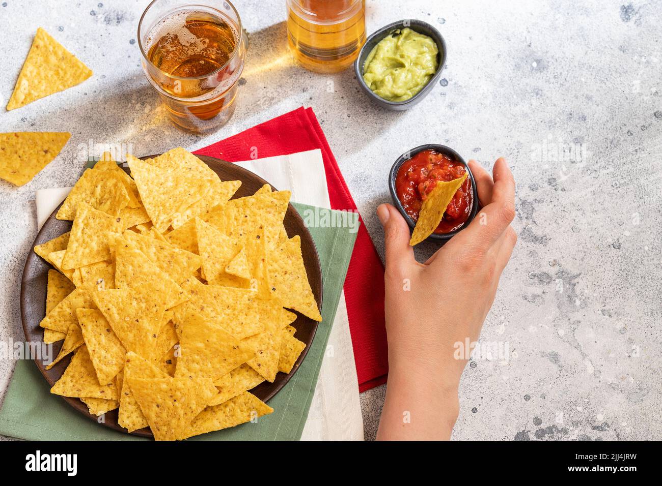 Female hand hold one of nachos, Mexican snack served with traditional ...