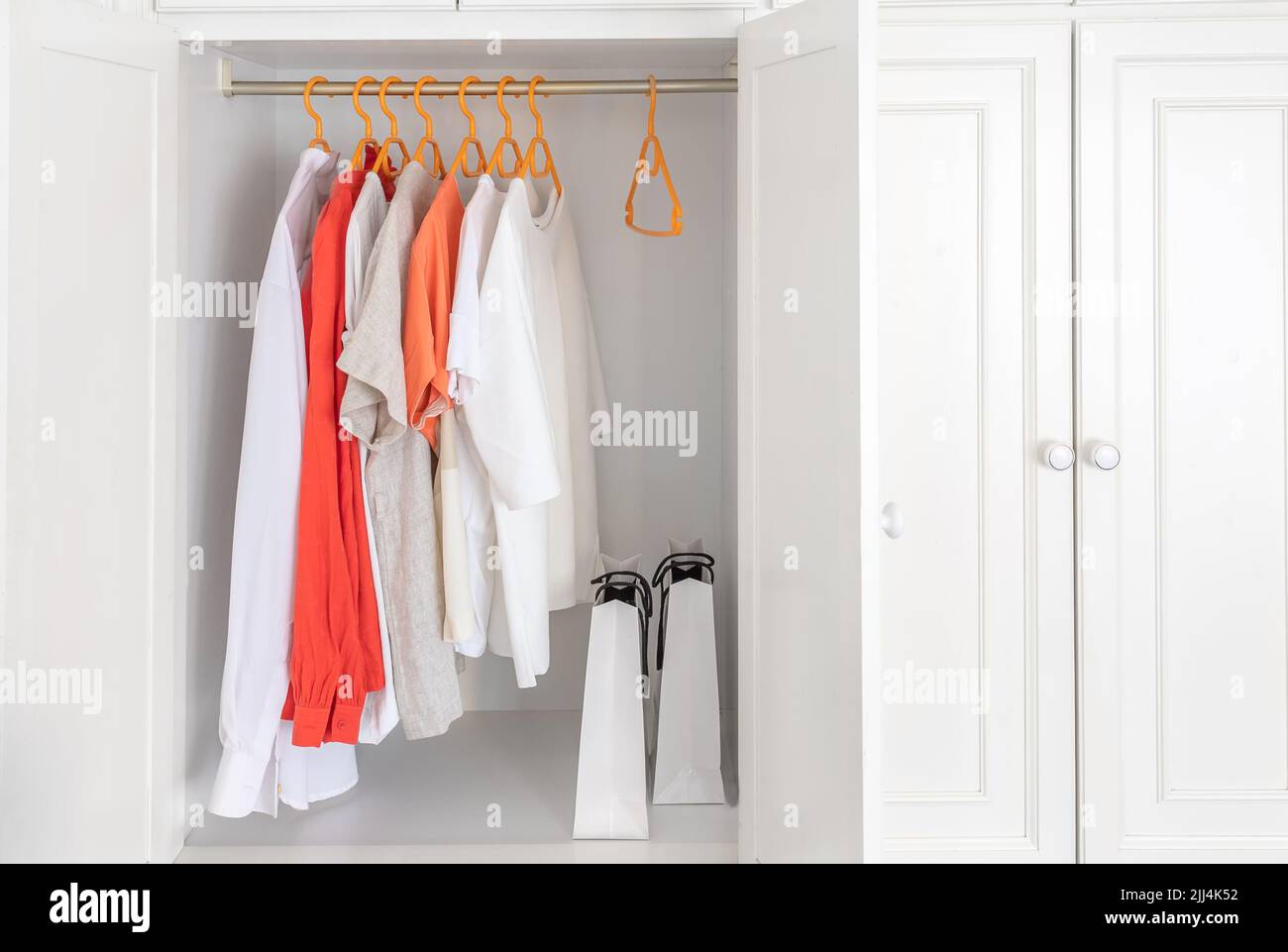 Collection of clothes hanging on rack in white wardrobe in dressing ...