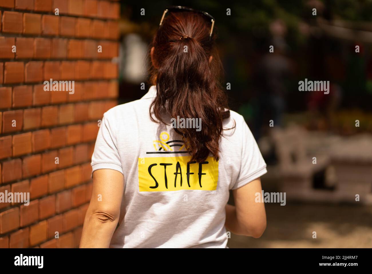 Staff member walking alongside a brick wall Stock Photo - Alamy