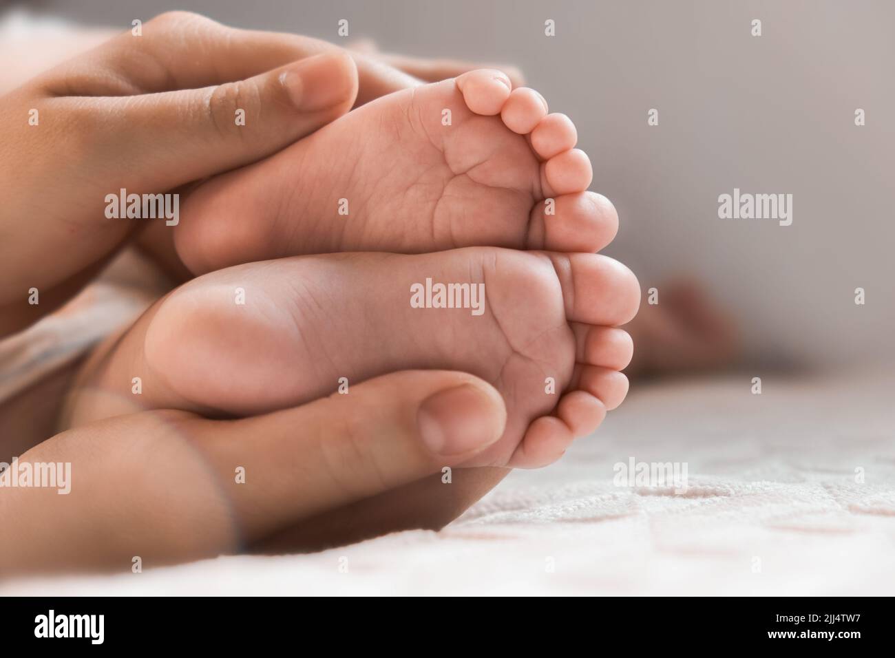 Mother holding Baby Feet in Hands. Legs Newborn in female parents Hand ...