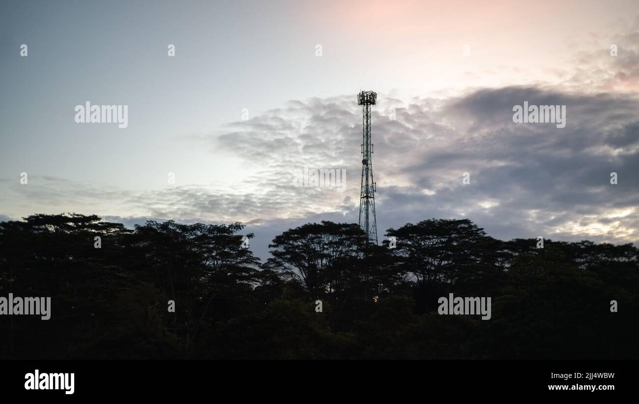Tall Telecommunication tower and the silhouetted treeline in the evening landscape view Stock ...