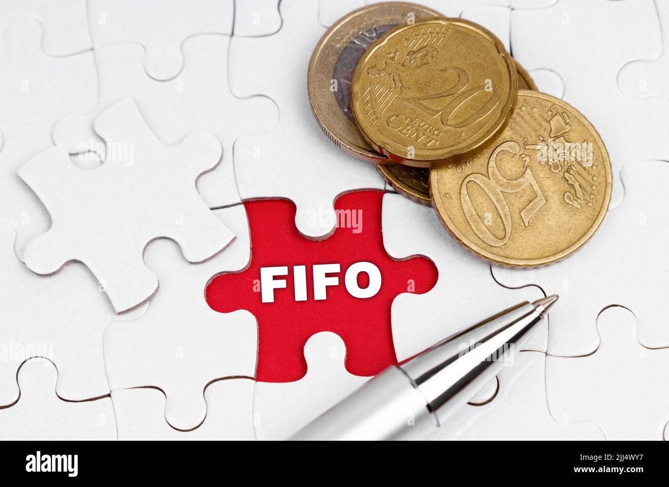 Business concept. On white puzzles there are coins and a pen, in the ...