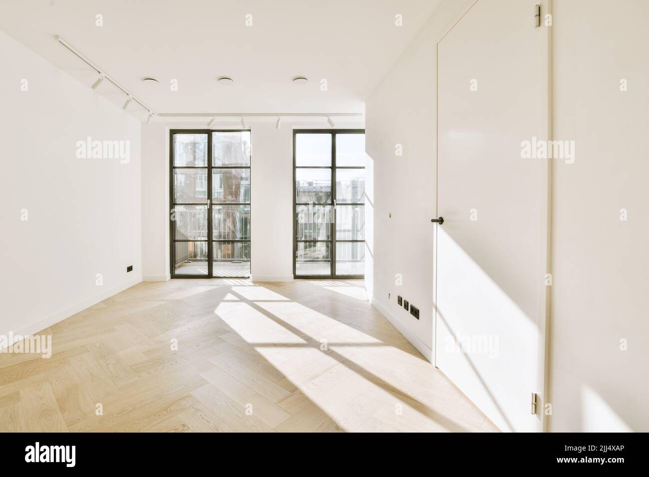 Interior of empty white room with large balcony windows and wooden ...