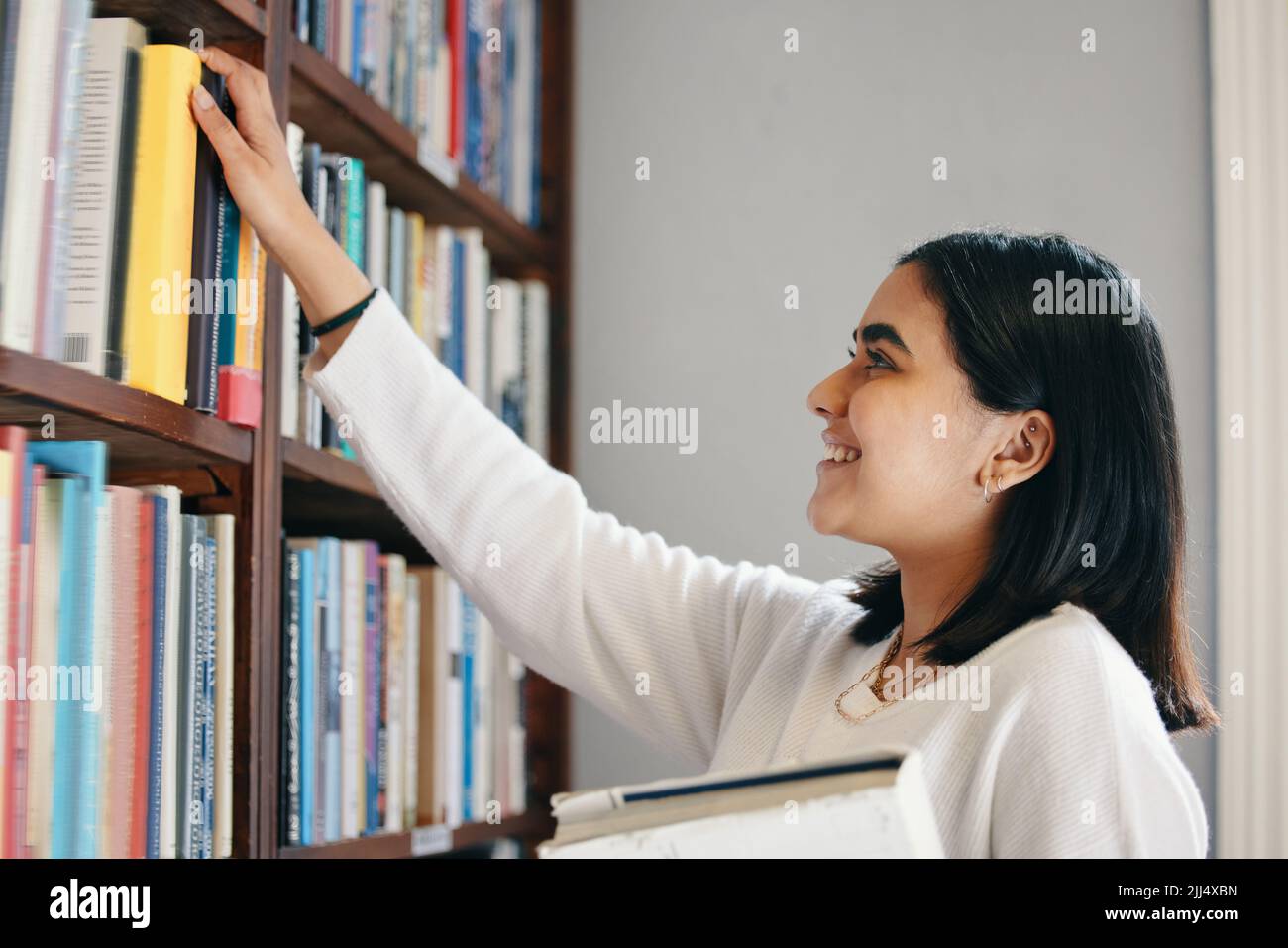The library has it all. a young woman reading a book in her school ...