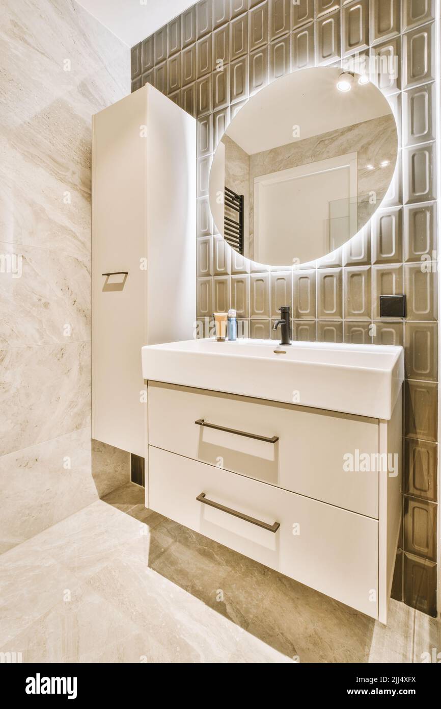 Sink with tap and liquid soap hanging on tiled wall under mirror in ...