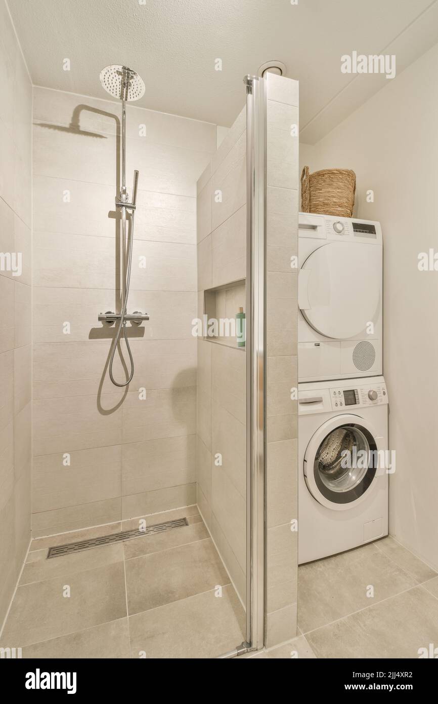 Shower faucets attached to tiled wall near glass partition and washing ...