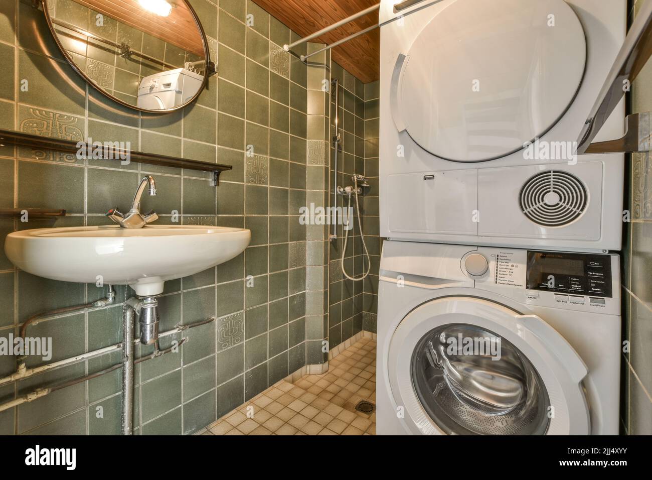 Bathroom with green tiled walls and sink near washing machine and ...
