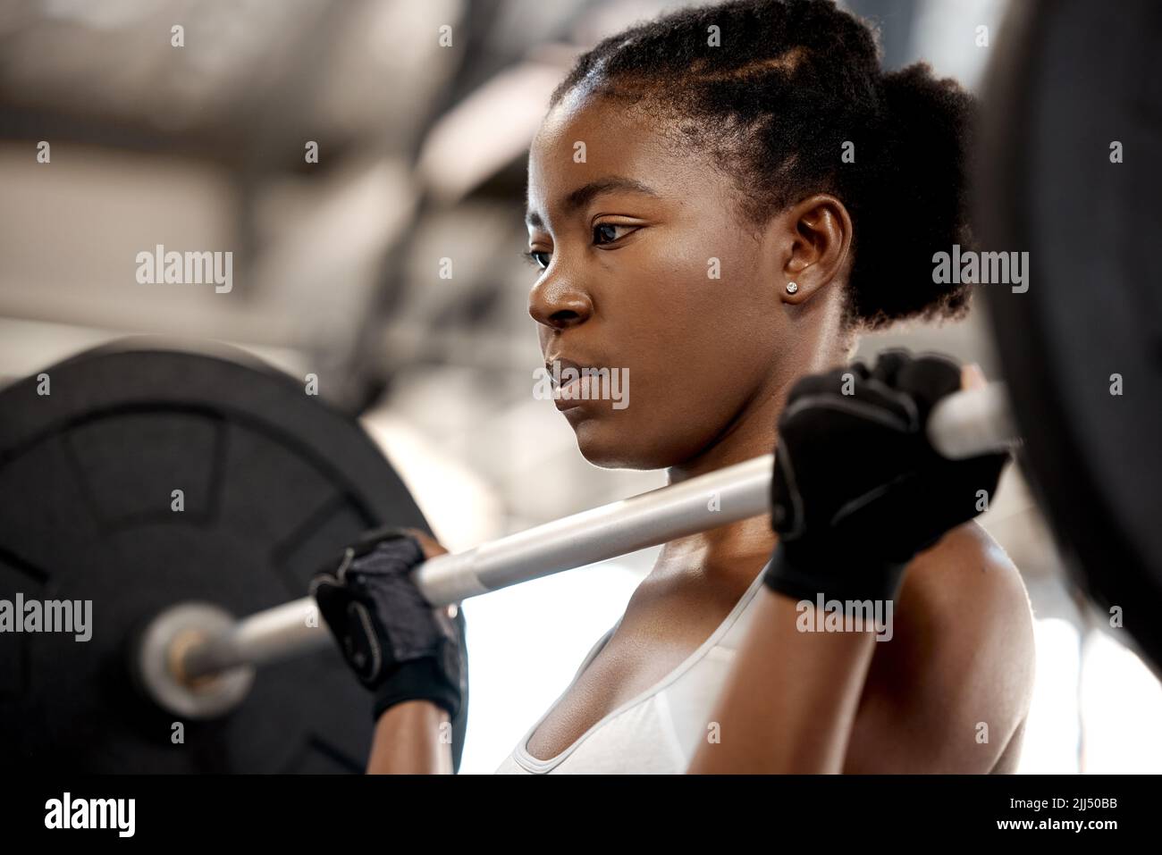 You cant fake strong. a sporty young woman exercising with a barbell in ...