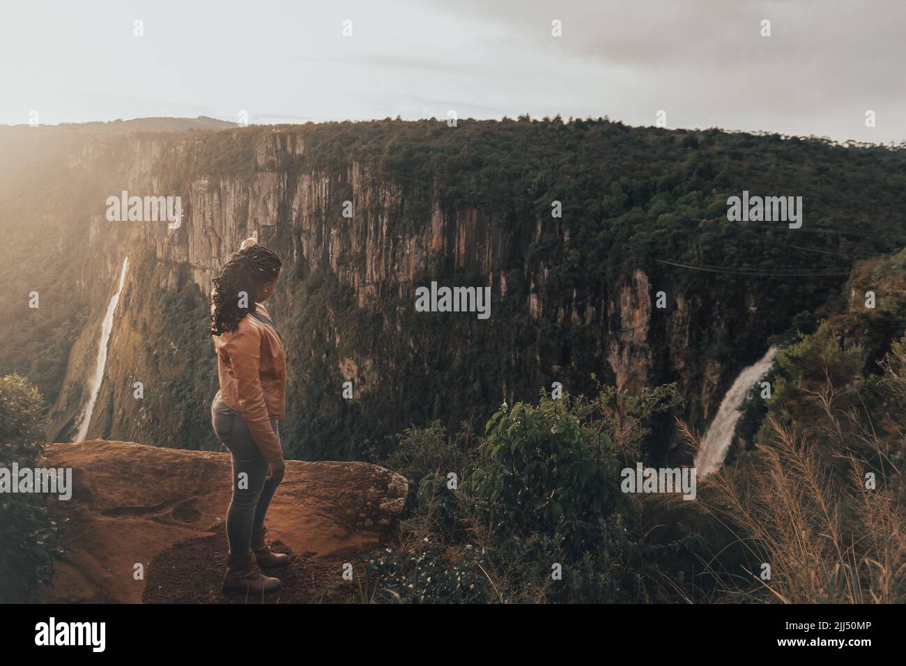 Young woman standing on the cliff at sunset Stock Photo - Alamy
