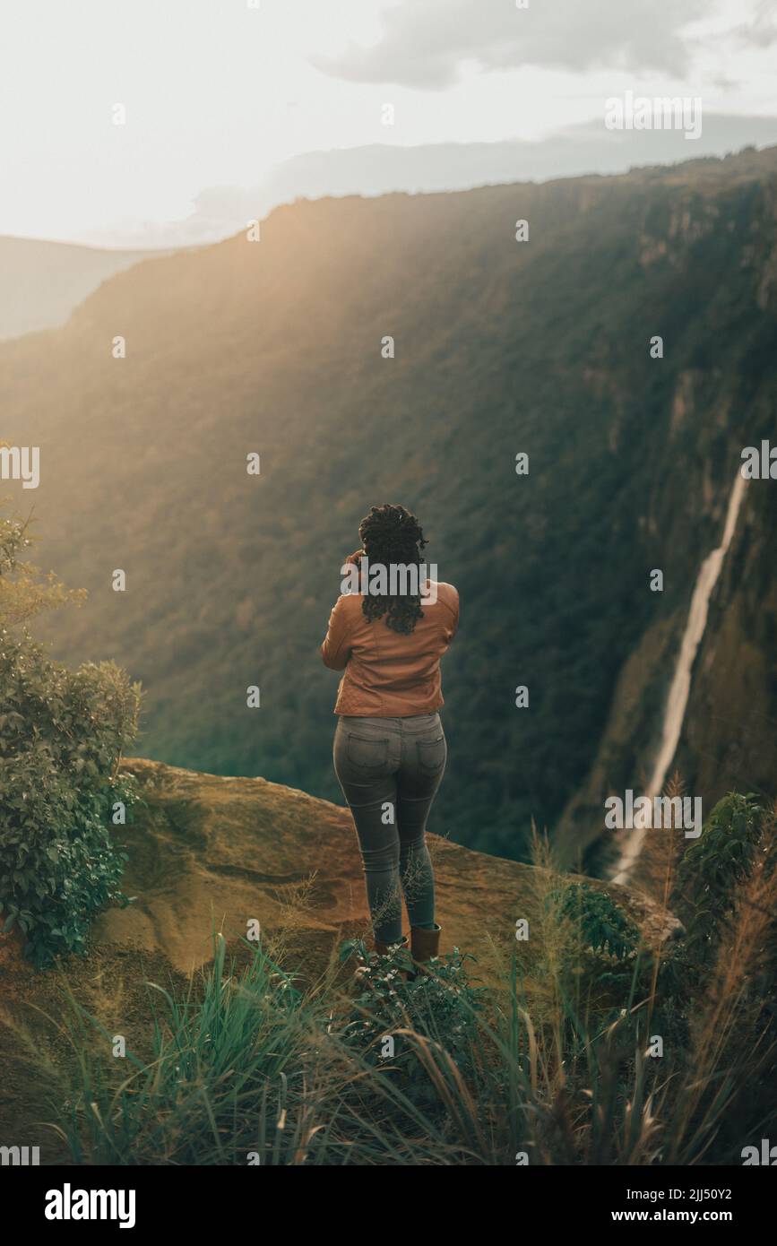 Young woman standing on the cliff at sunset Stock Photo - Alamy