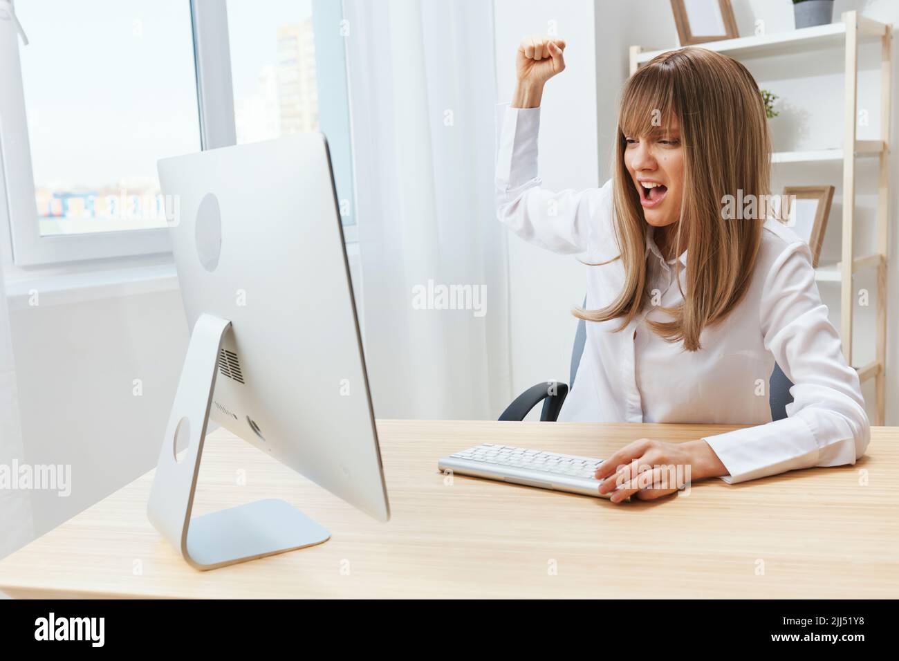Angry evil blonde businesswoman screaming to desktop shaking fist at ...