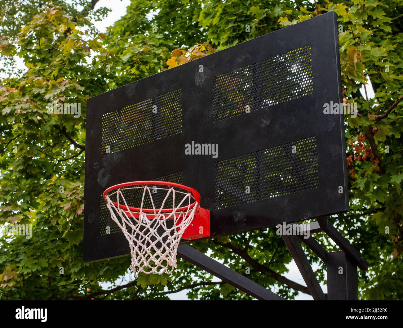 A red hoop on a black metal backboard on a basketball court in a park ...