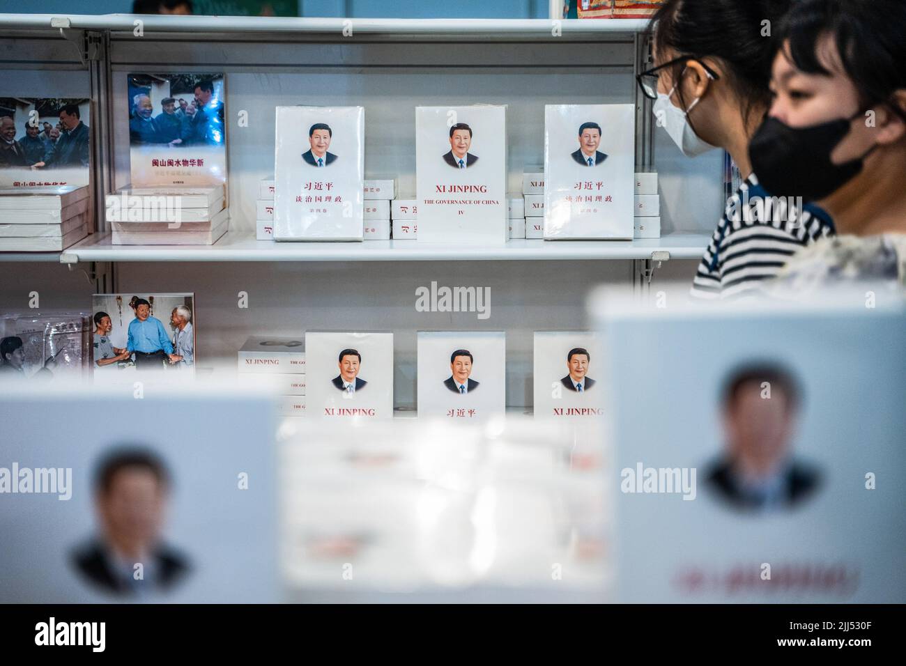 People wearing masks walk by books of Chinese President Xi Jinping's ...
