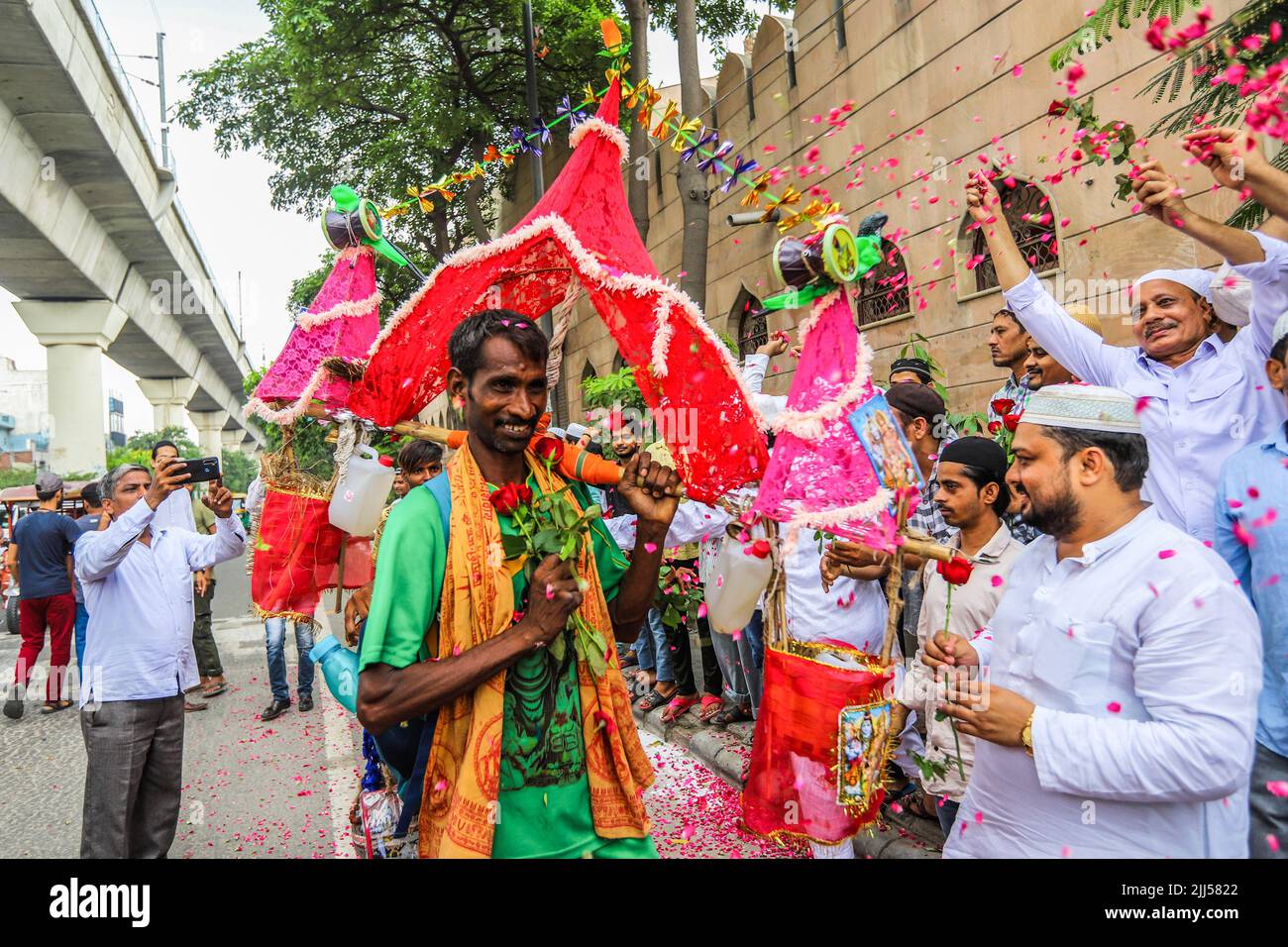 People belonging to Muslim community shower flower petals on Kanwariyas, devotees of the Hindu ...