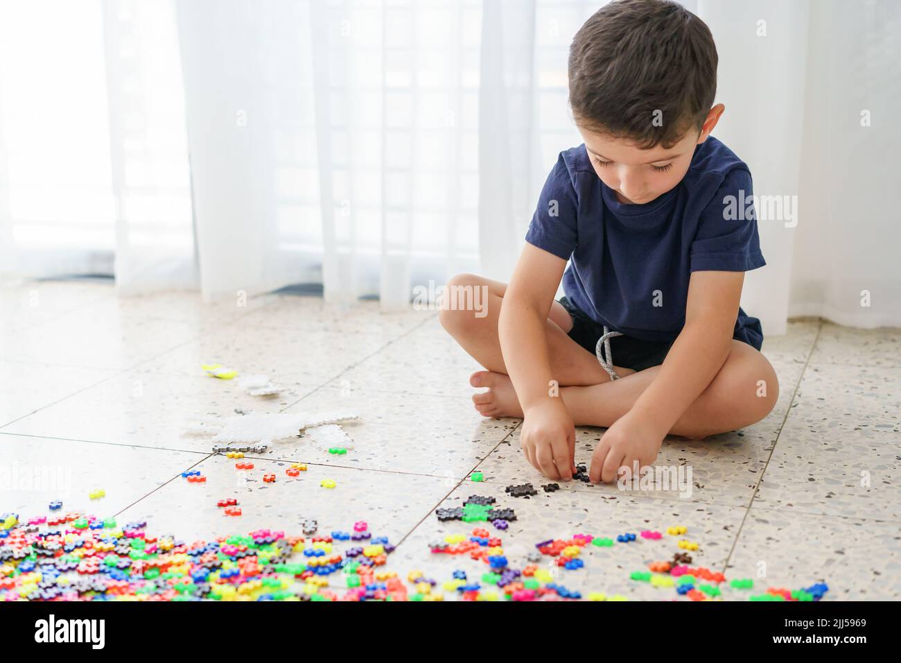 Little boy sitting on the floor at home playing with colorful plastic ...