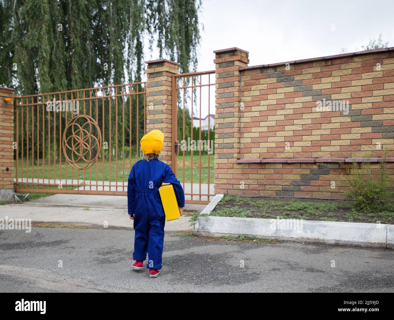 unrecognizable boy in a blue uniform stands with his back with a yellow ...
