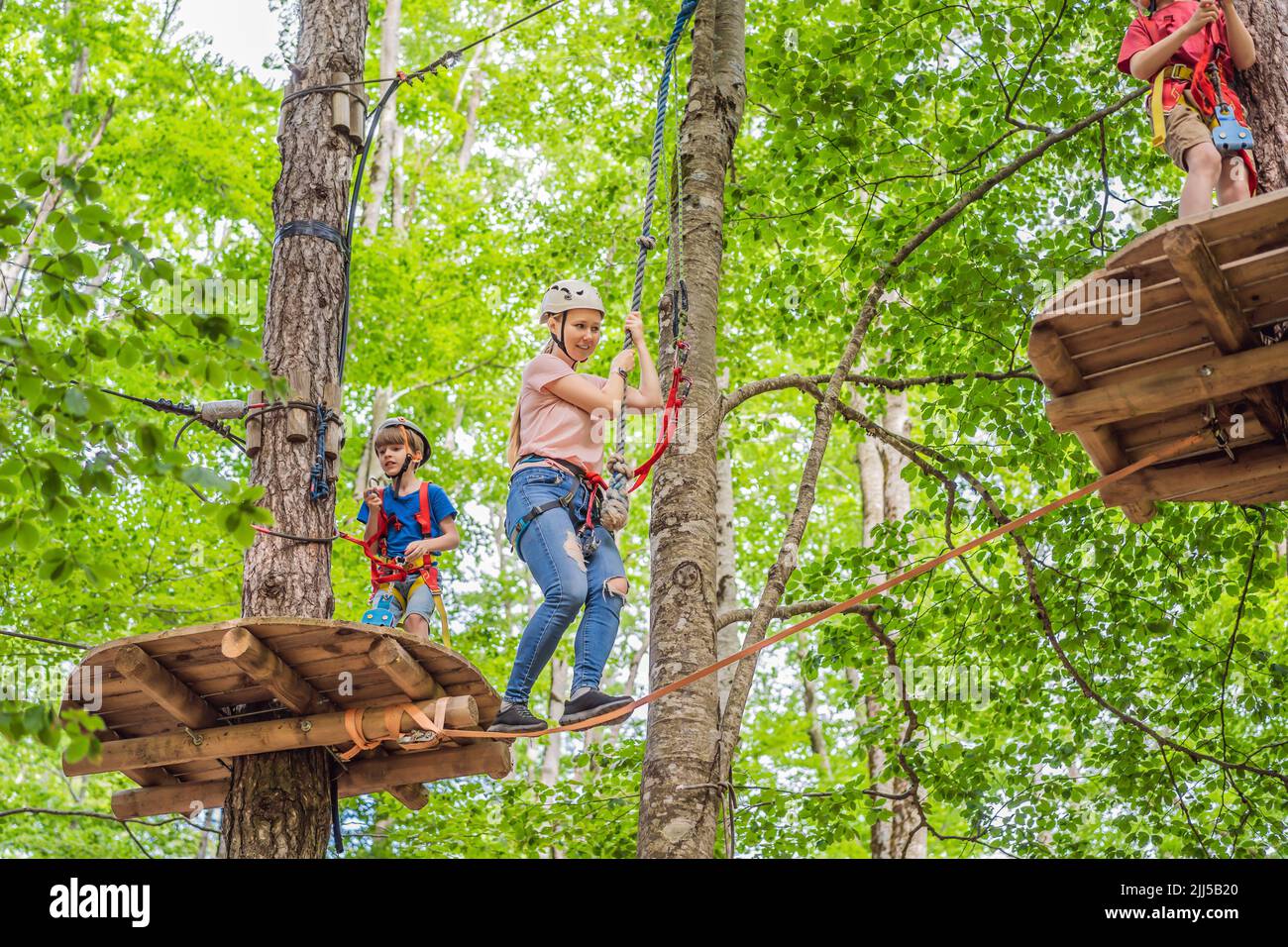 Mother and son climbing in extreme road trolley zipline in forest on ...