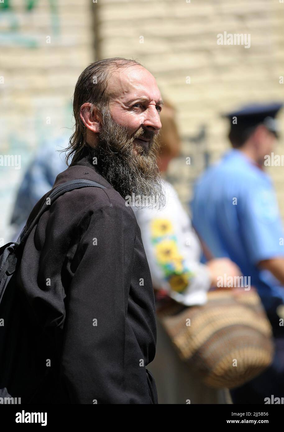 Middle aged monk in a cassock walking down the street, portrait. July ...