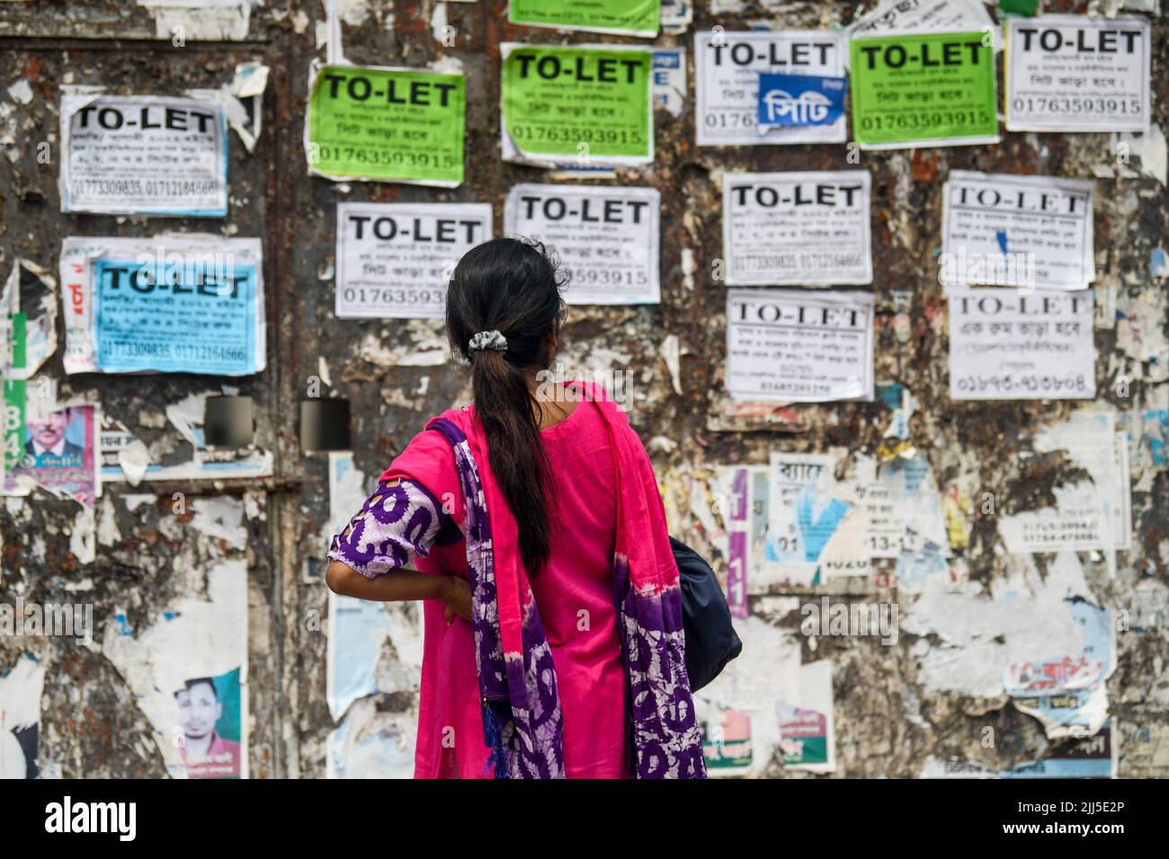 A woman is looking for To-Let beside road's wall in Dhaka. (Photo by Piyas Biswas / SOPA Images ...