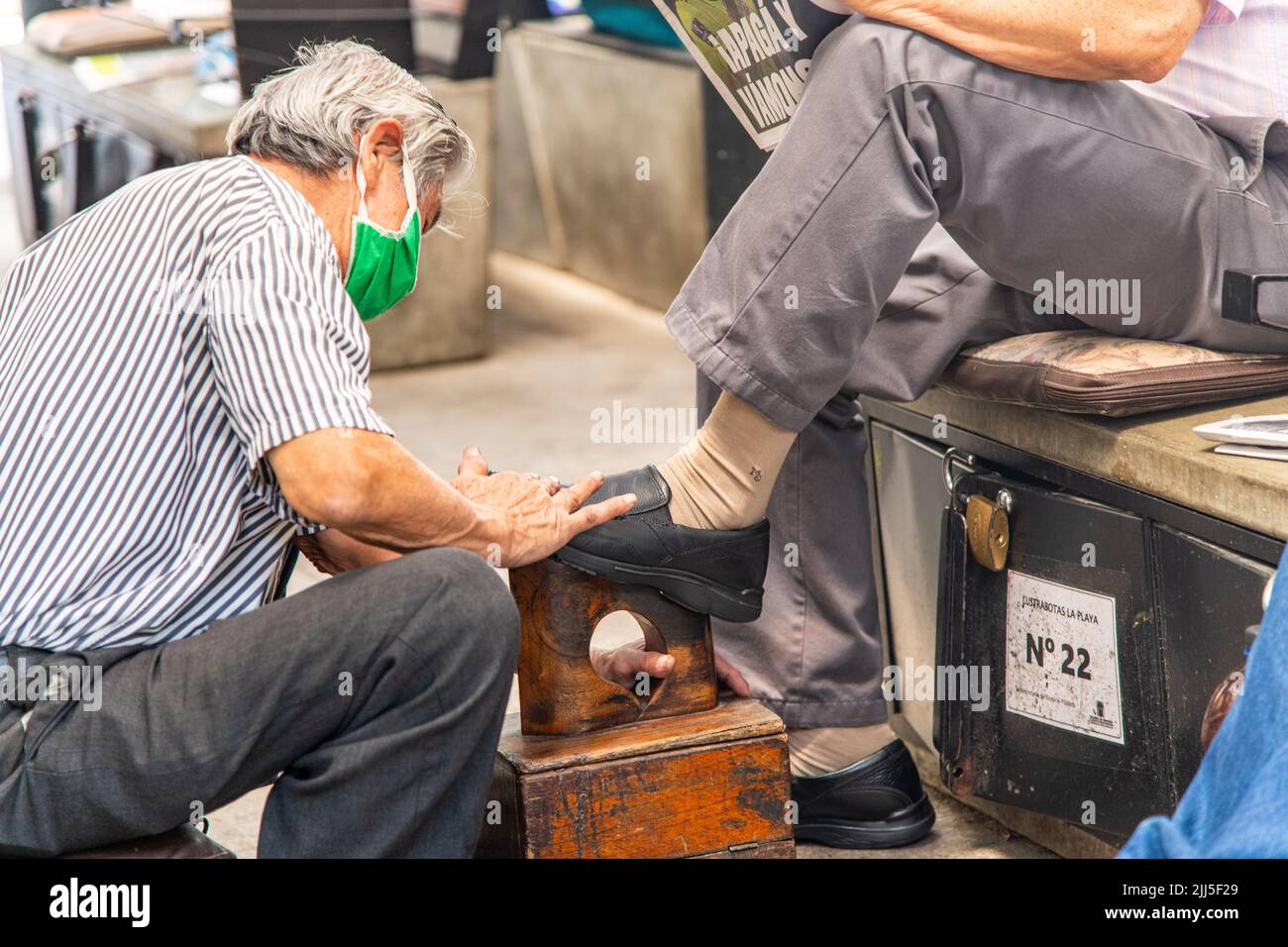 A shoeshiner shining the shoes of a man in Medellin, Colombia Stock ...