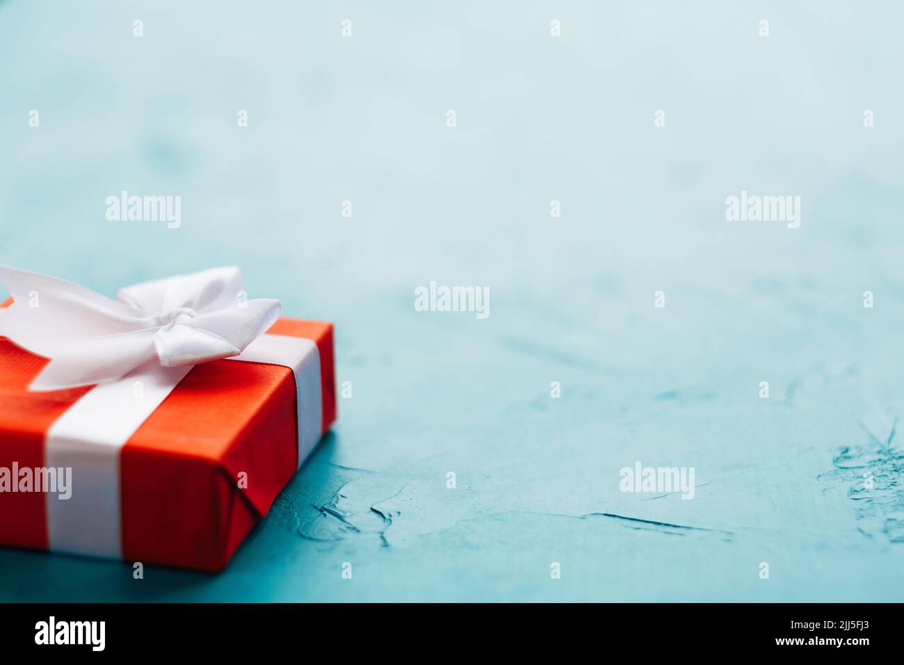 Red closed gift box on blue background Stock Photo - Alamy