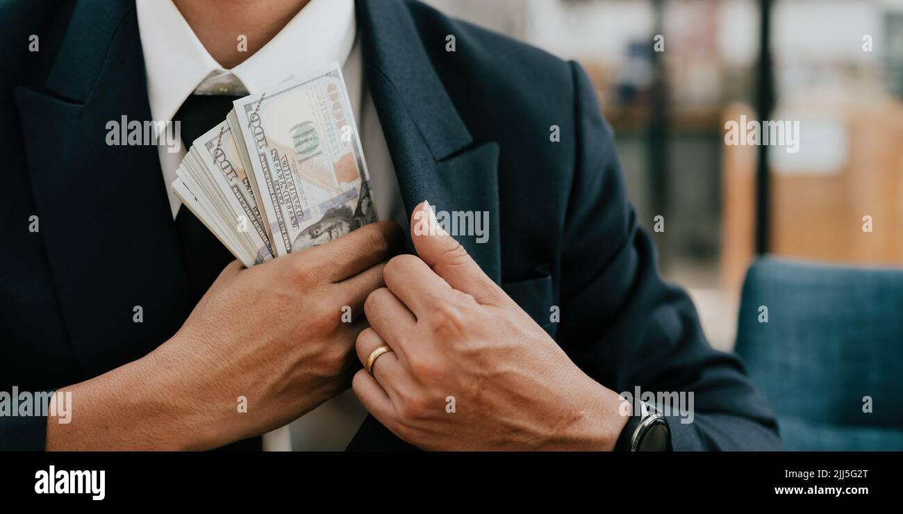 Closeup conceptual photo of bribed man putting money in the suit pocket ...