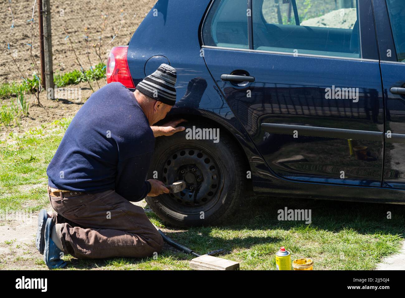 Mechanic changing wheel on car with manual wrench. Mechanic replacing ...