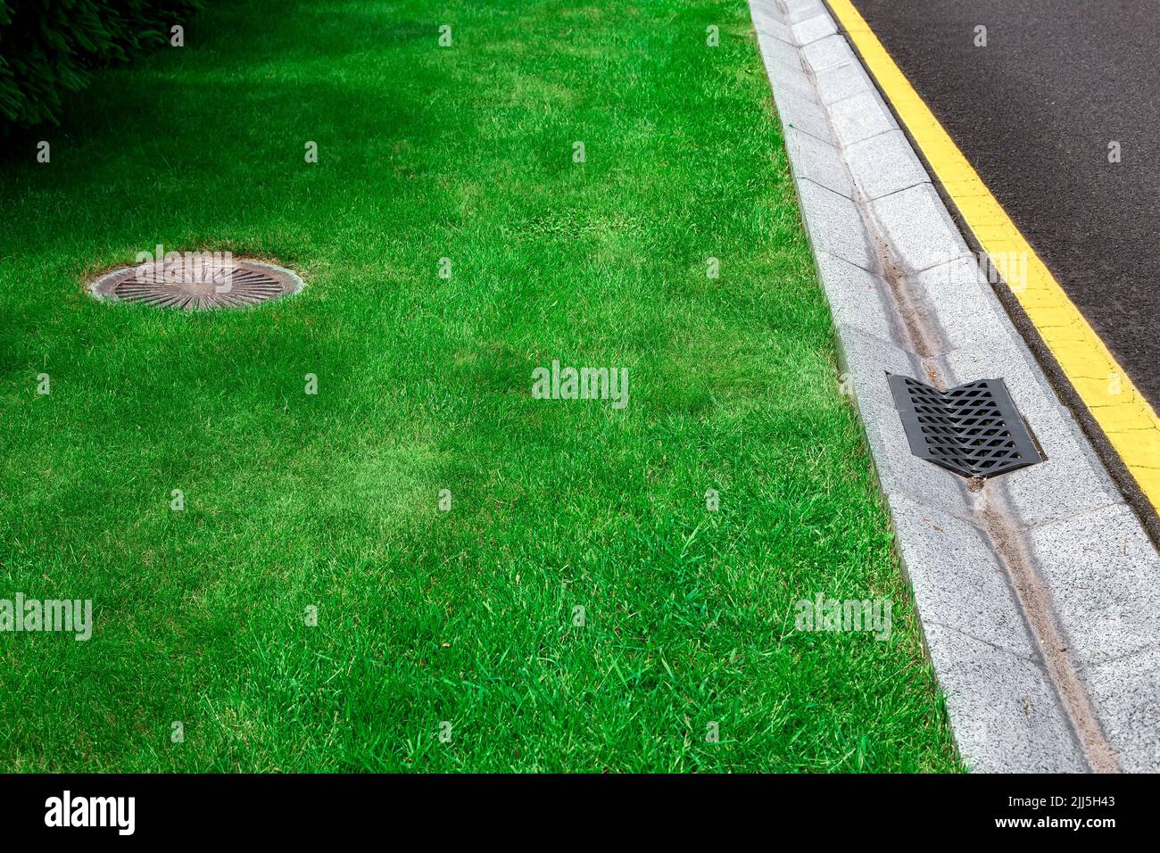gray gutter of a stormwater system on the side of asphalt road with ...