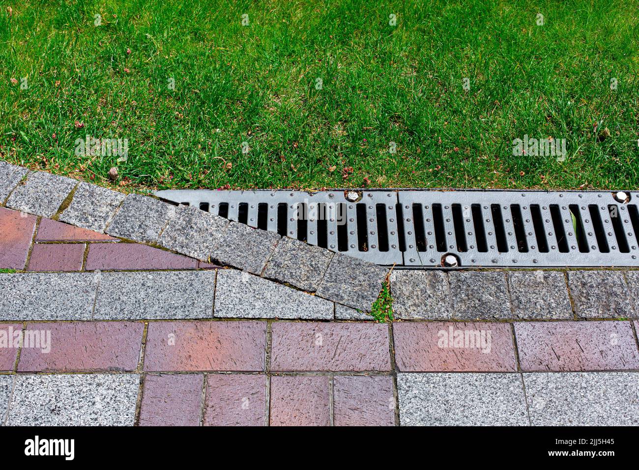 drainage grate bolted to storm drain at corner of pavement walkway path ...