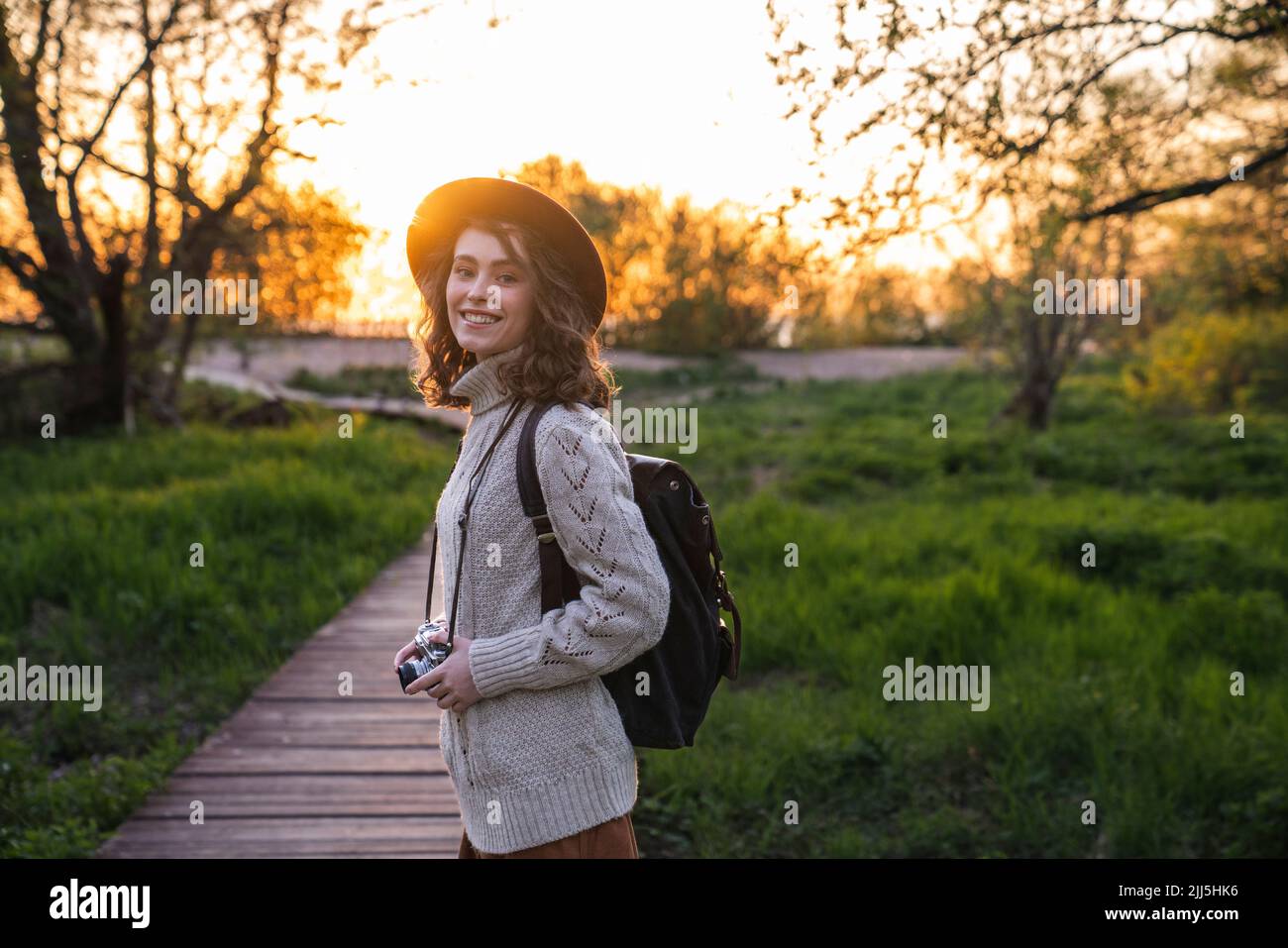 Happy woman with camera standing in park Stock Photo - Alamy