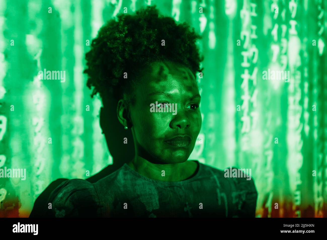 Digital code falling on woman with Afro hairstyle in front of wall ...