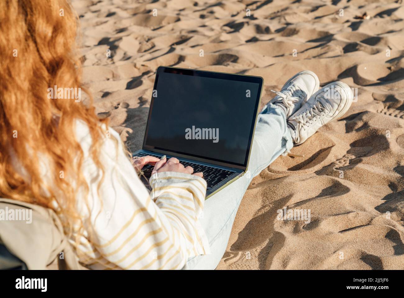 Woman e-learning through laptop at beach Stock Photo - Alamy