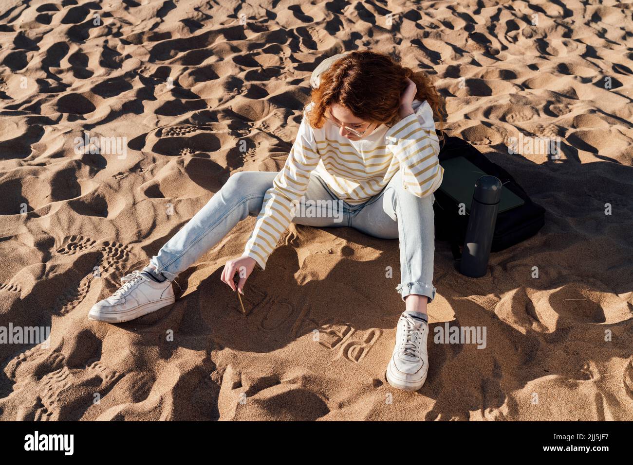 Young woman writing on sand at beach Stock Photo - Alamy