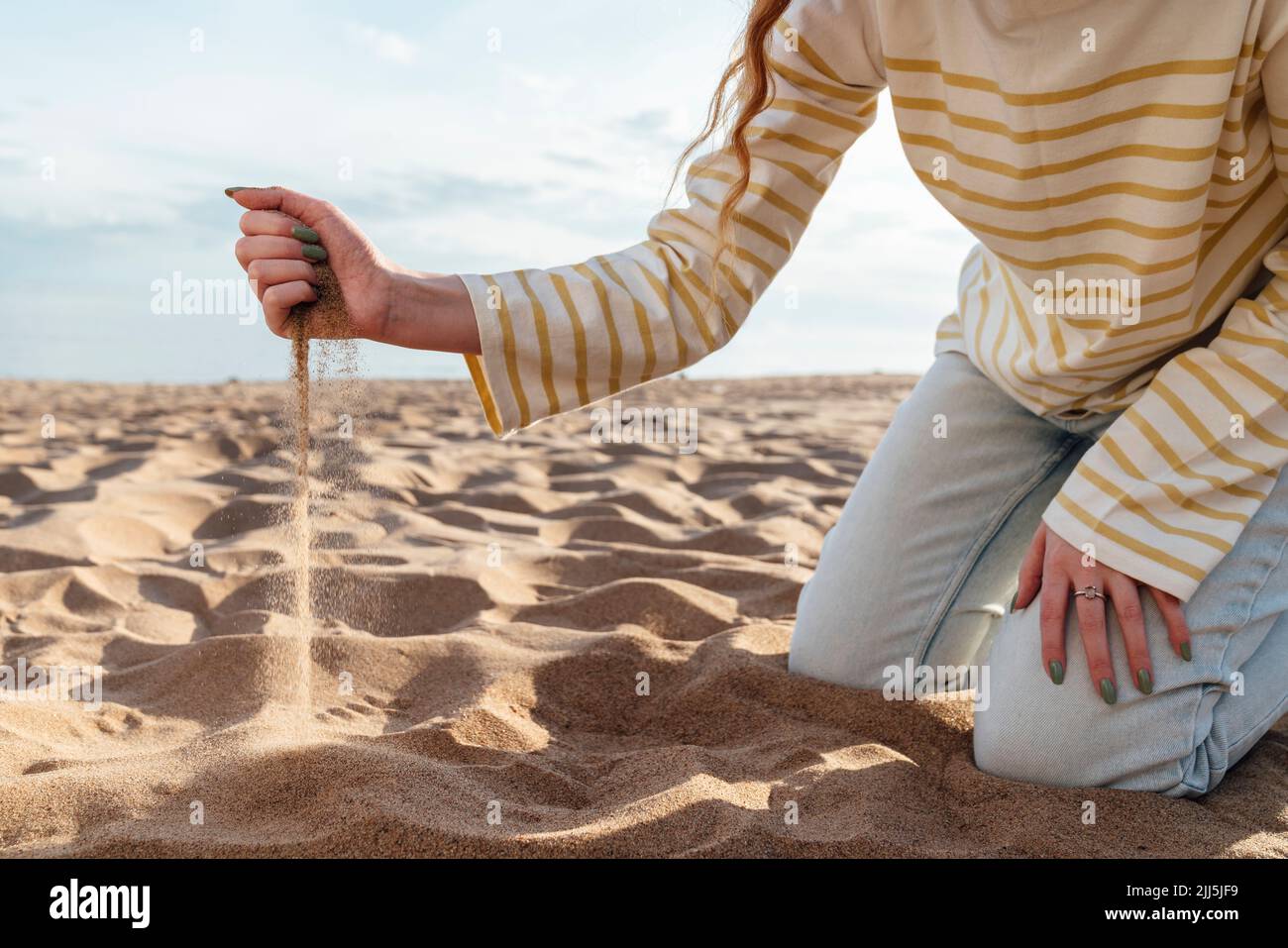Sand spilling from woman's hand at beach Stock Photo - Alamy