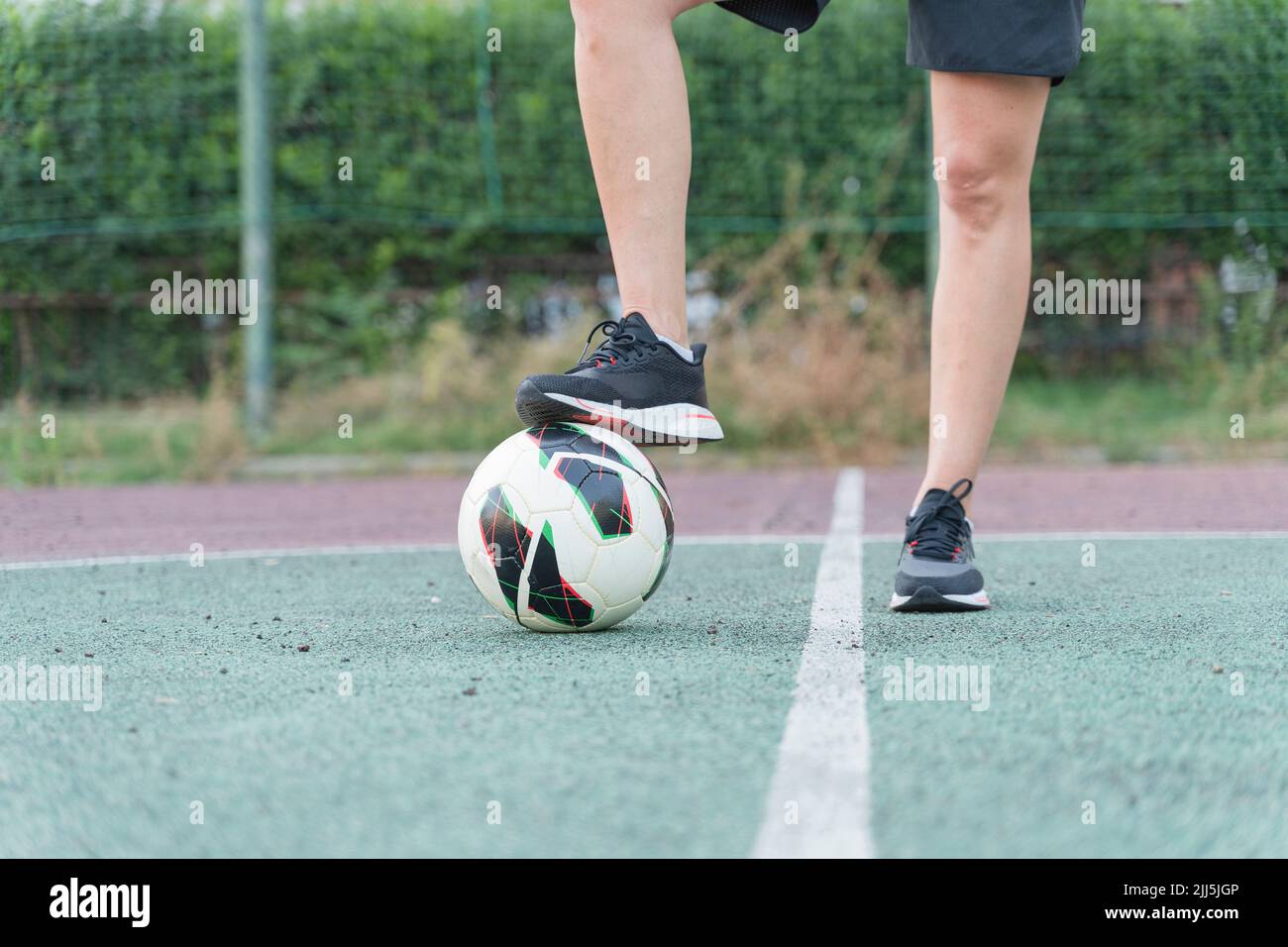 Woman with leg on soccer ball in sports court Stock Photo - Alamy
