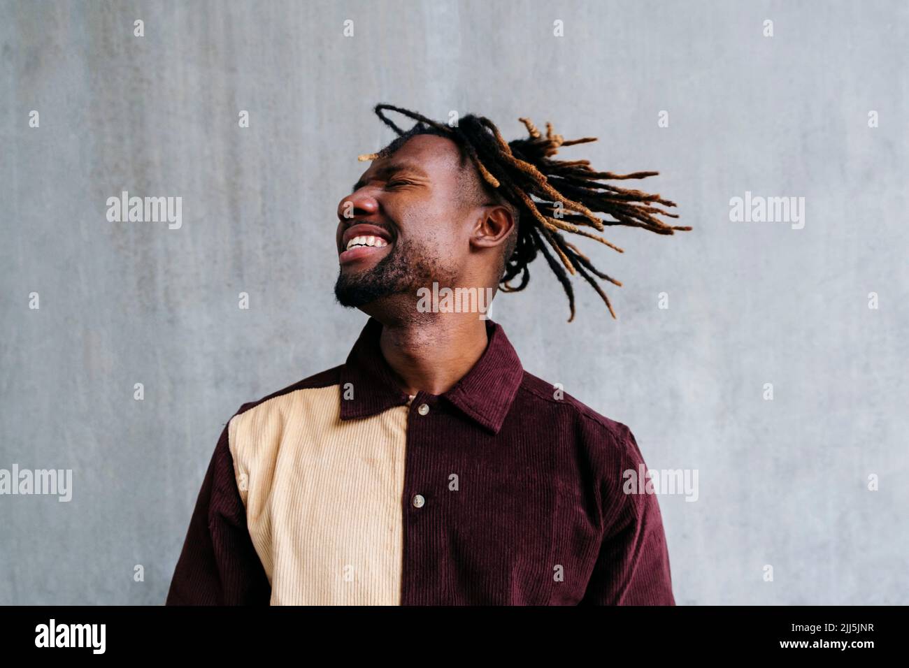 Happy man tossing hair in front of wall Stock Photo - Alamy