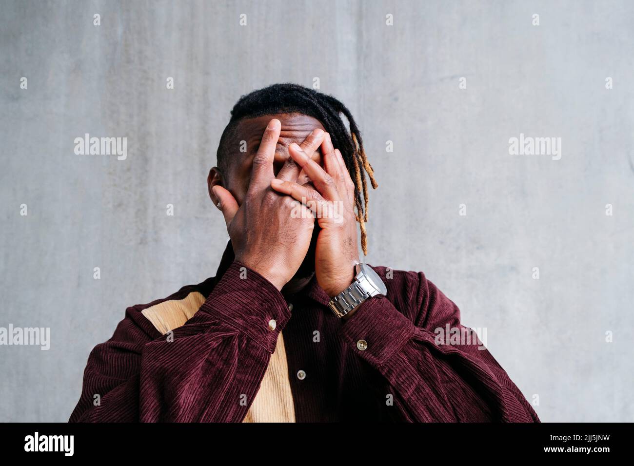Man covering face with hands in front of wall Stock Photo - Alamy