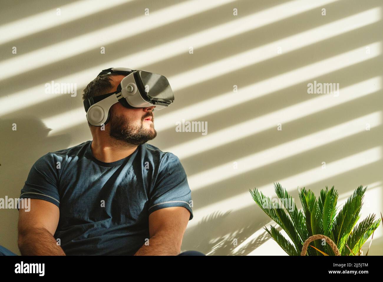 Man watching through VR glasses in front of wall Stock Photo - Alamy