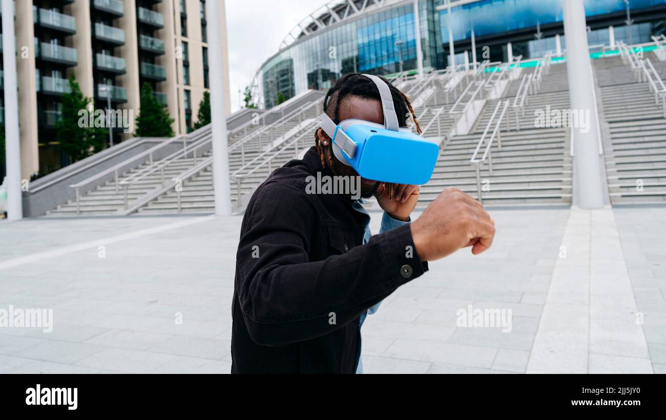 Man standing in fighting stance wearing virtual reality headset in ...