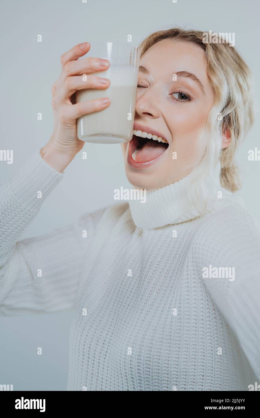 Young woman holding glass of plant milk screaming against white ...