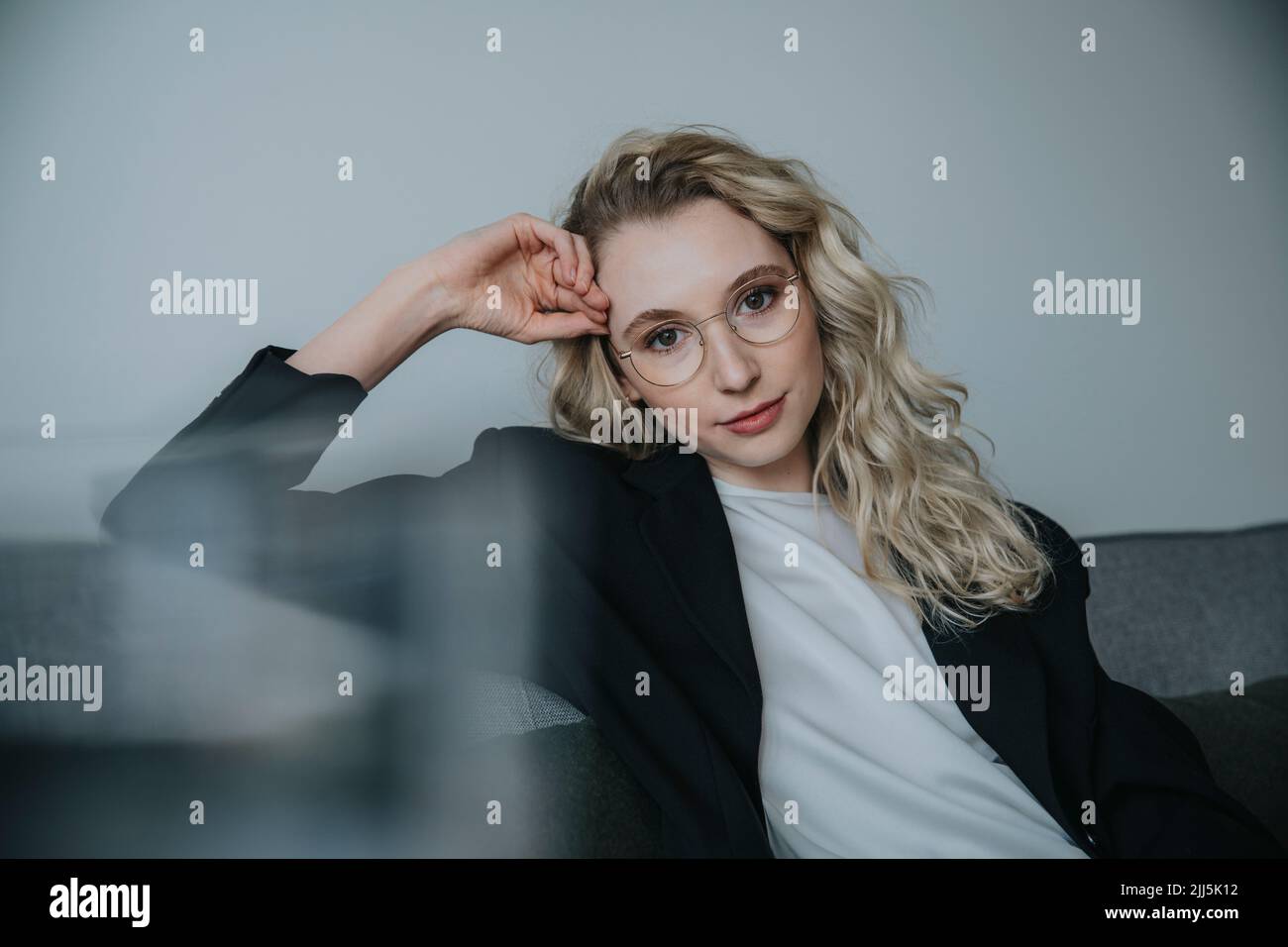 Blond businesswoman wearing eyeglasses resting on sofa Stock Photo - Alamy