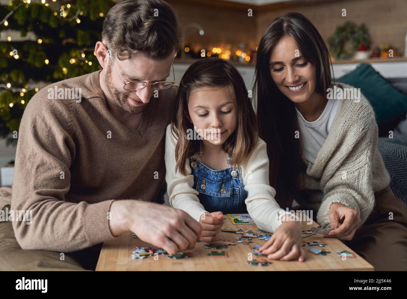 Smiling parents with daughter joining puzzle at home Stock Photo - Alamy
