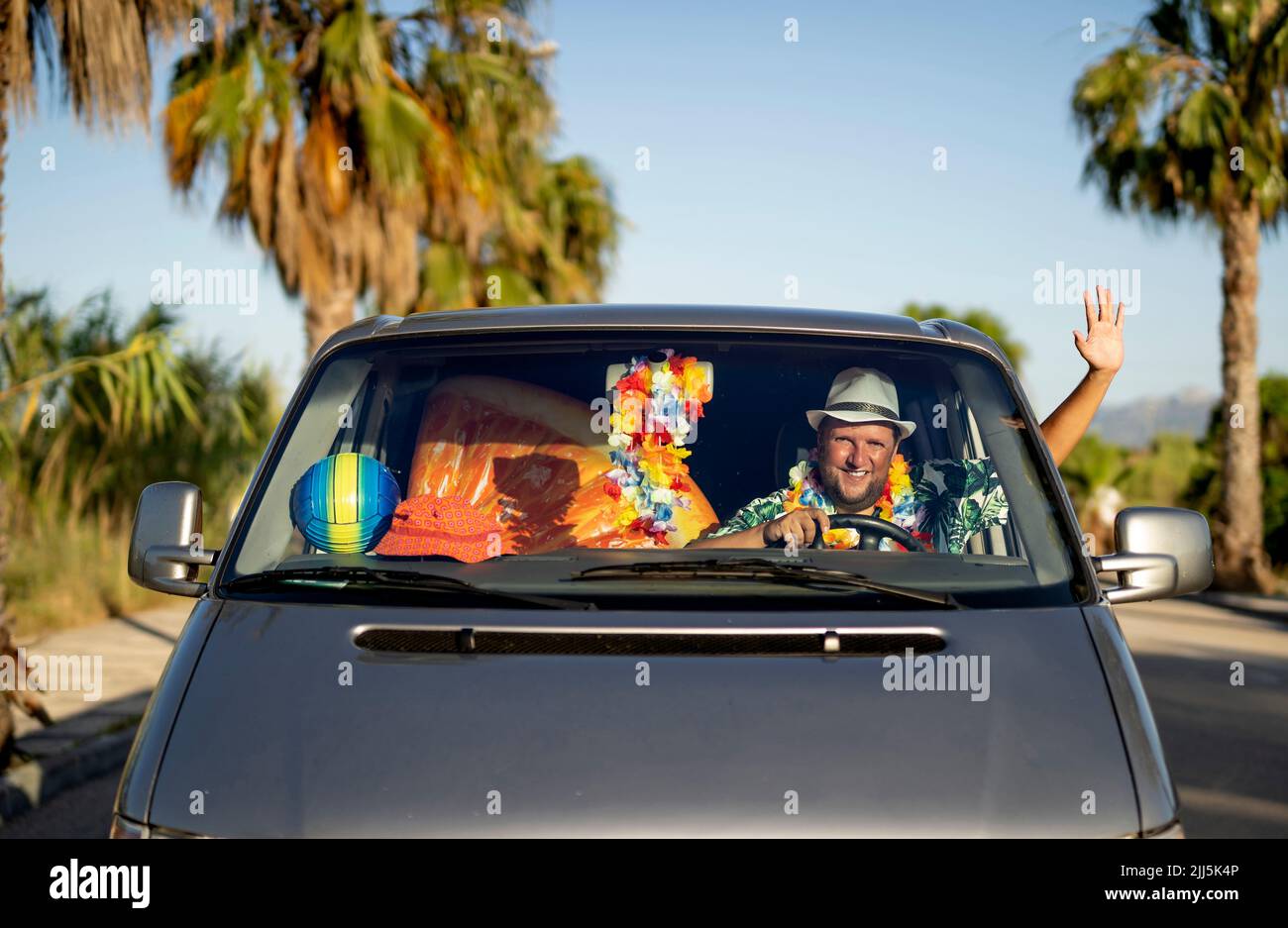 Happy man driving car waving hand through window Stock Photo - Alamy