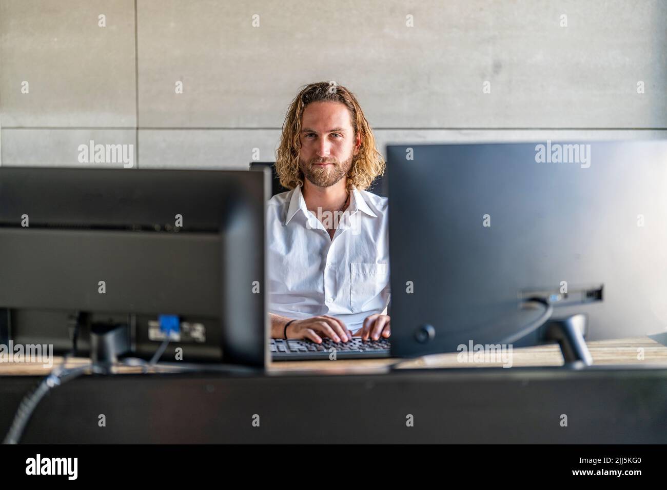 Confident executive with computers at desk in office Stock Photo - Alamy