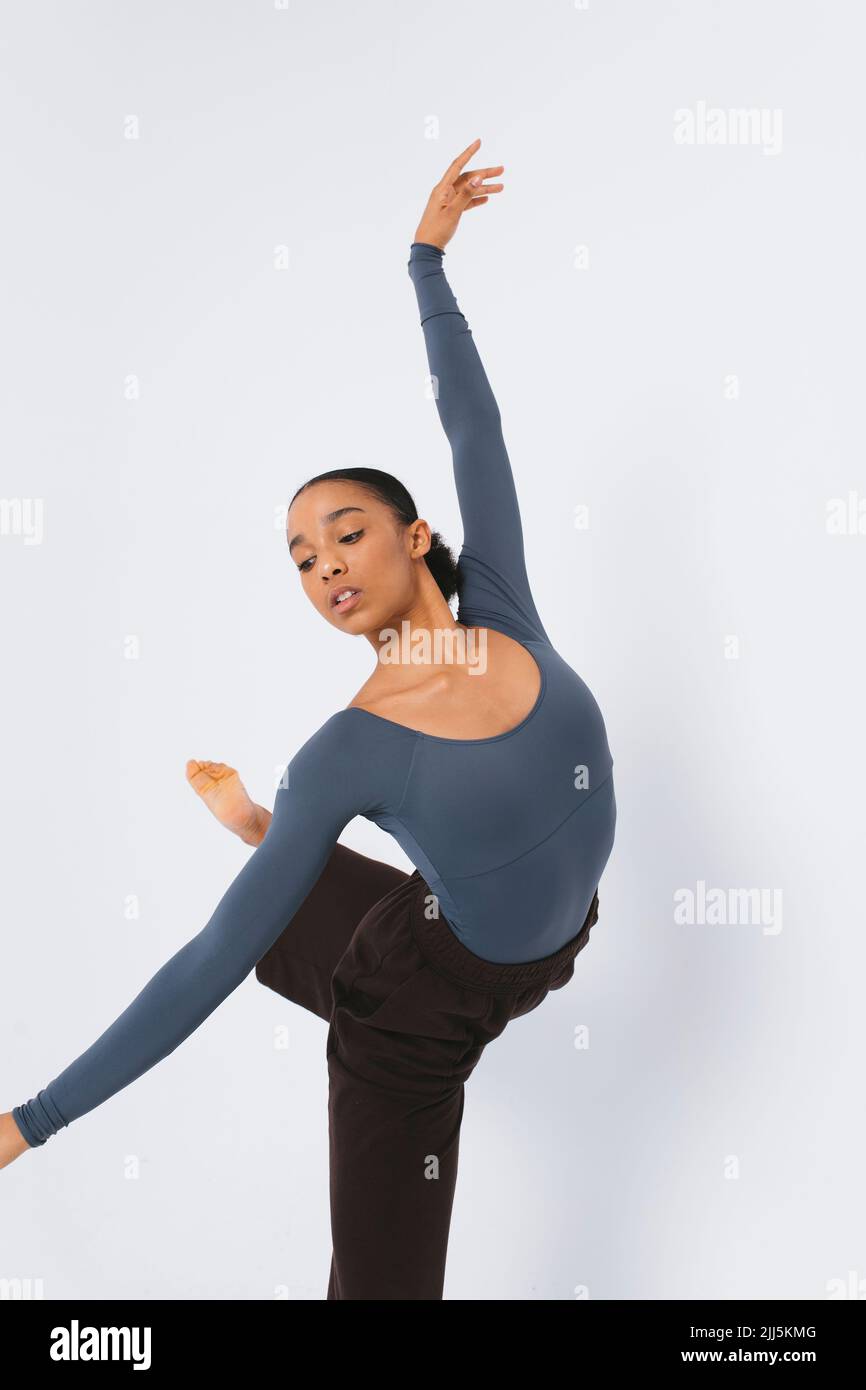 Young ballet dancer with arm raised against white background Stock ...