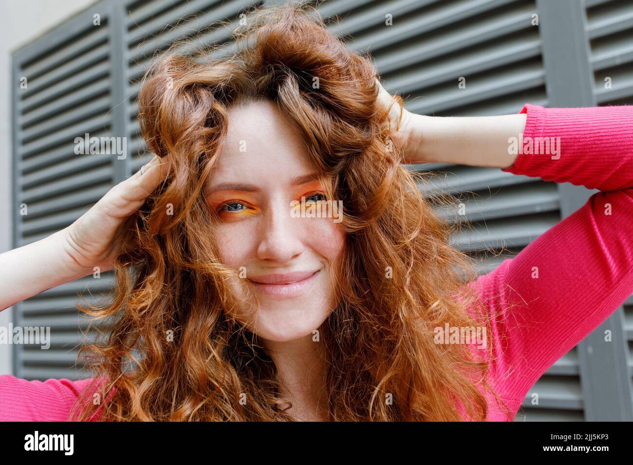 Happy redhead woman with hands in hair Stock Photo - Alamy