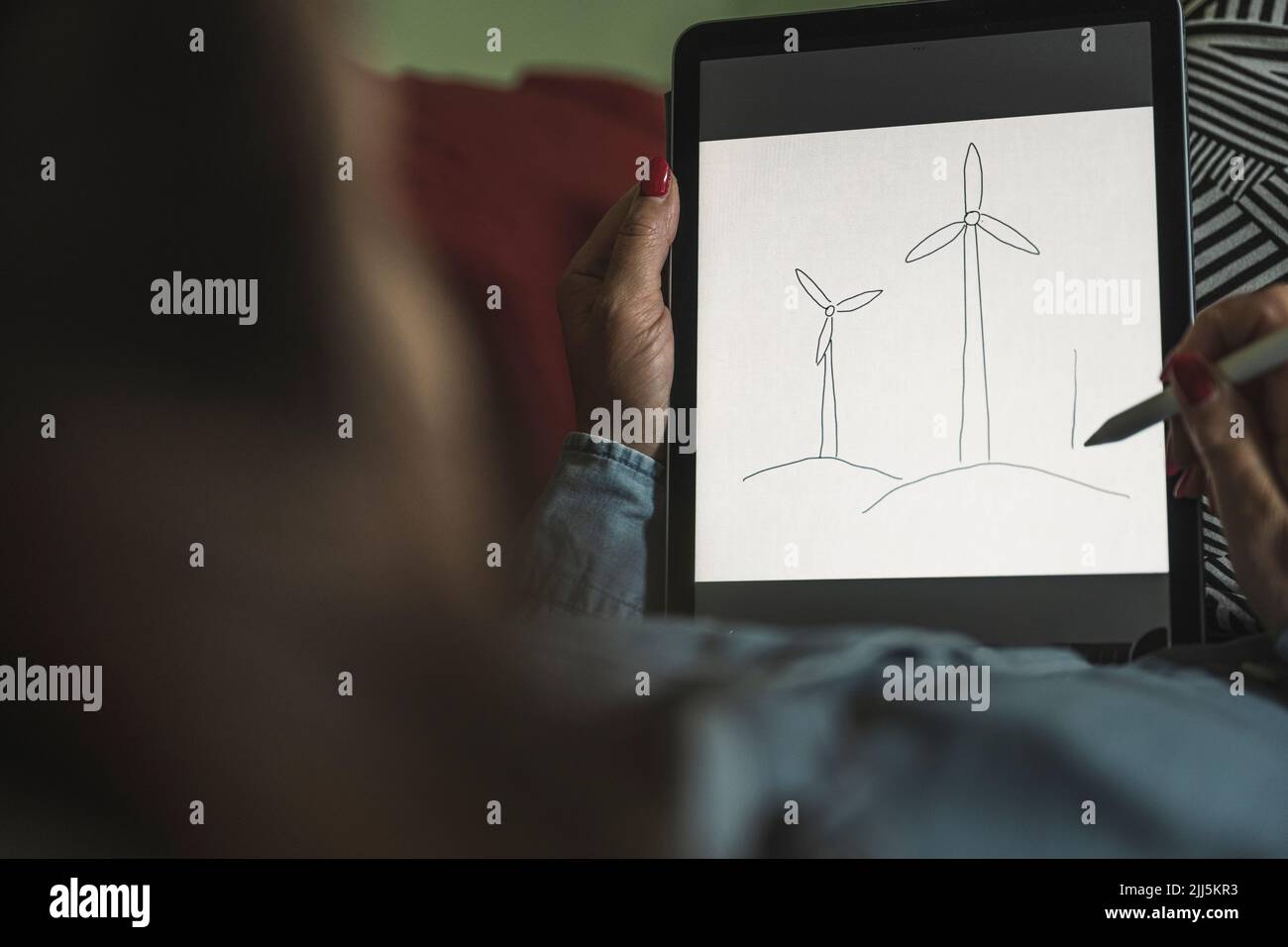 Freelancer making sketch of wind turbines on graphics tablet at home ...