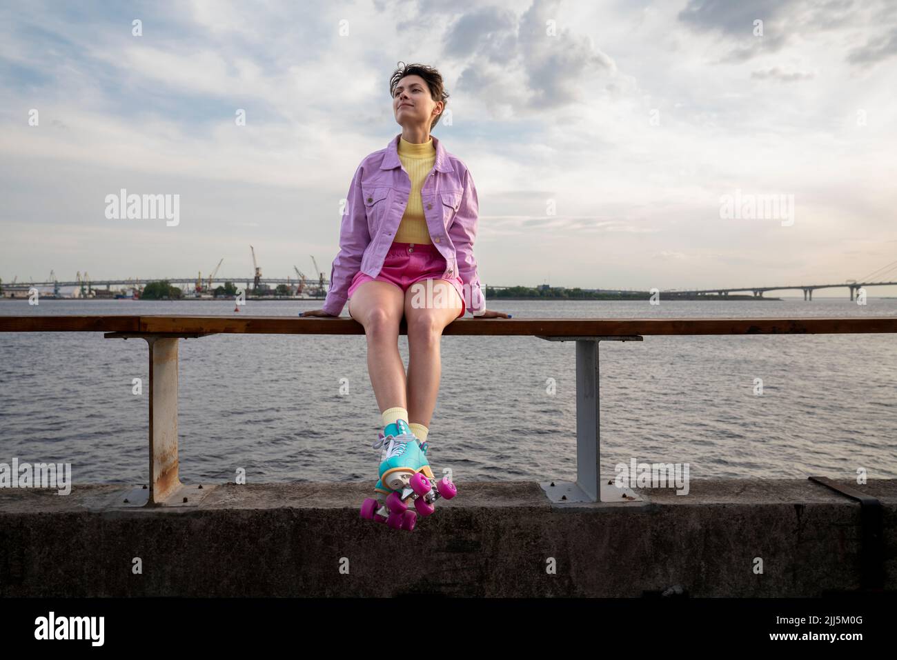 Woman wearing roller skates sitting on railing Stock Photo - Alamy