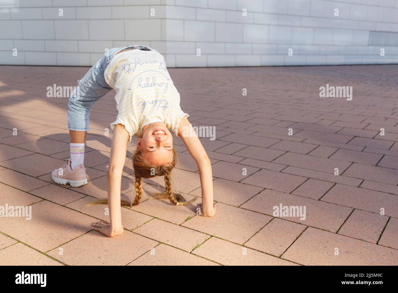 Happy girl standing in bridge position on floor Stock Photo - Alamy